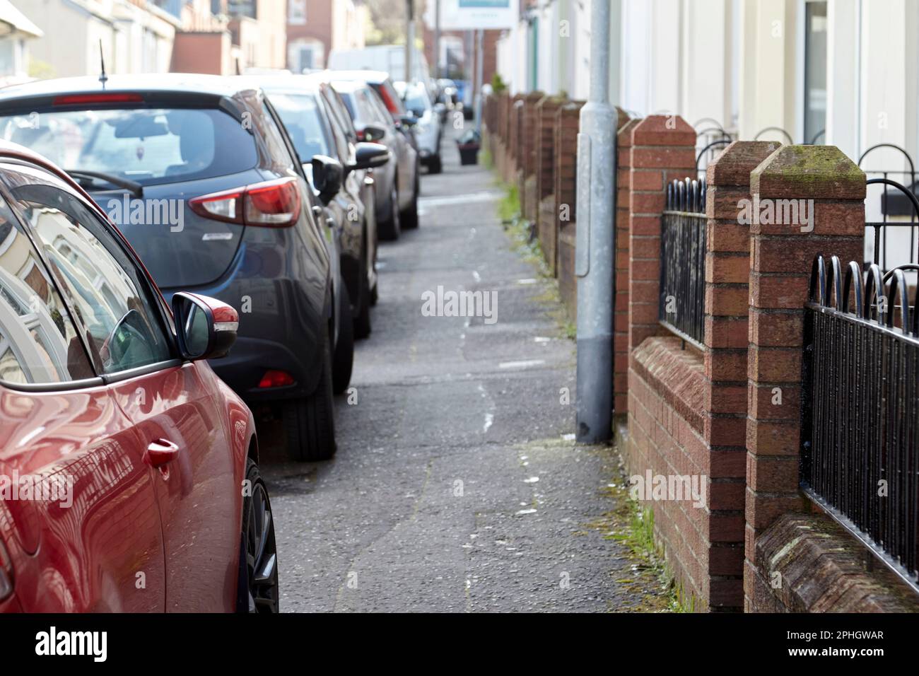cars parked on pavement making footpath narrow on residential street in ...