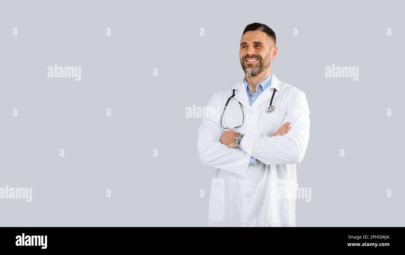 Medical worker. Happy male doctor in uniform posing with folded arms ...
