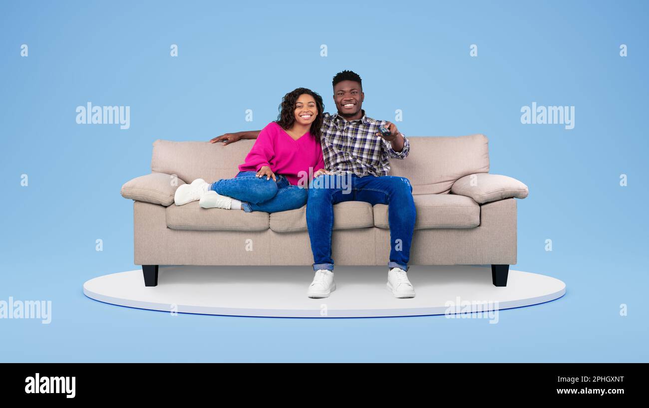 Glad young black couple with remote control sit on sofa, watch TV on ...