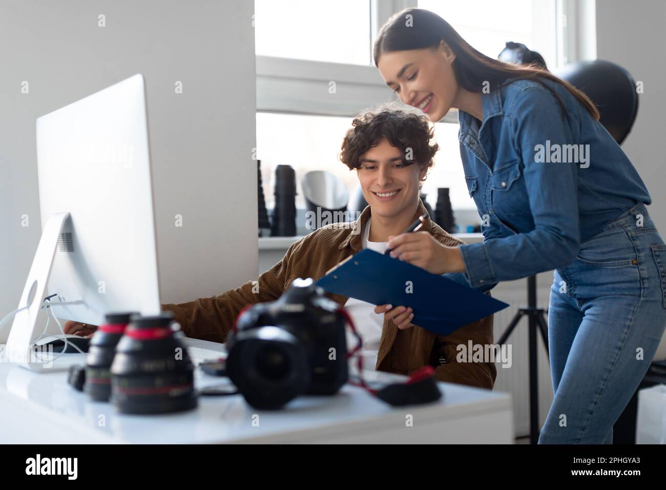 Female photo assistant with checklist and male photographer working ...