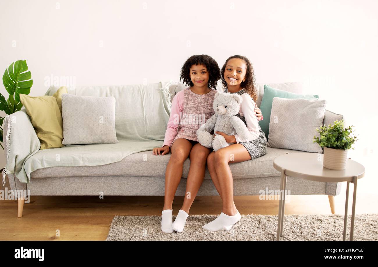 Two Black Siblings Sisters Hugging Posing Sitting On Couch Indoors ...
