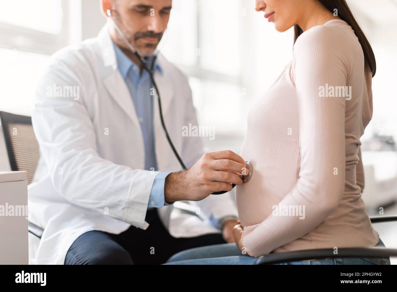 Healthcare and prenatal care concept. Male doctor examining pregnant ...