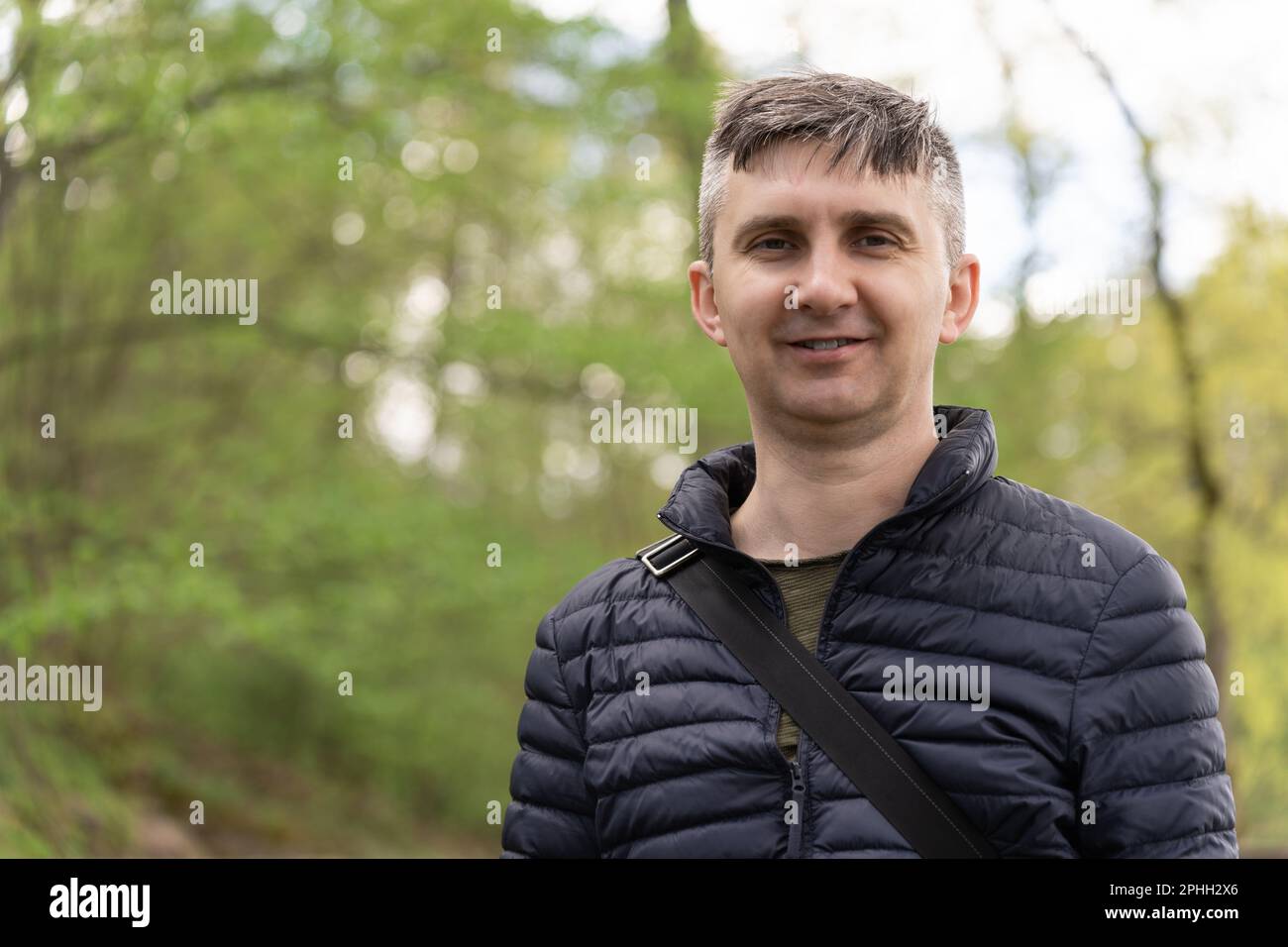 A middle-aged man with graying in a thin down jacket in early spring ...