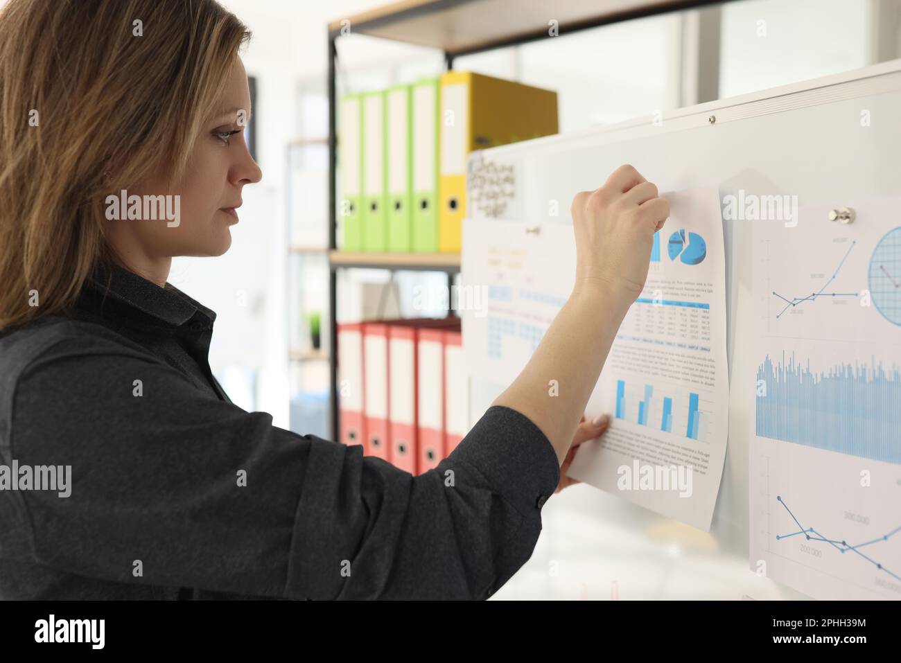 Woman puts paper with infographic charts on board in office Stock Photo ...