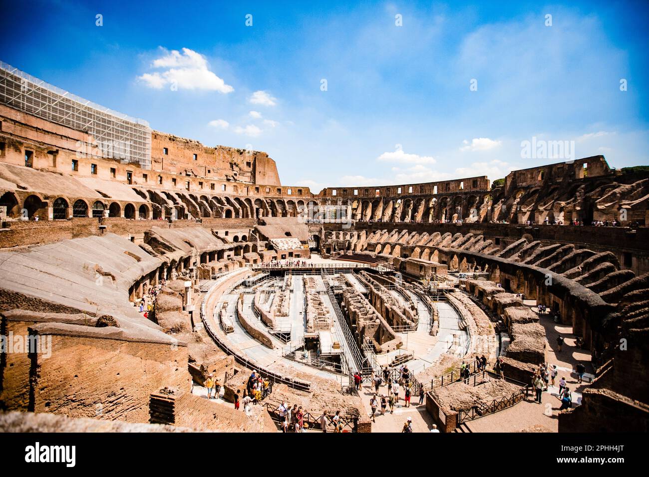 A group of people walking around the arena of the Colosseum on a sunny ...