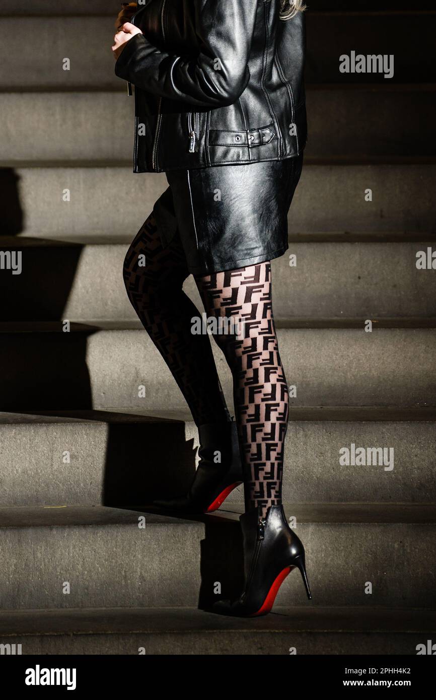 A Woman In Textured Tights High Heels A Leather Skirt And A Jacket Posing On The Stairs Stock