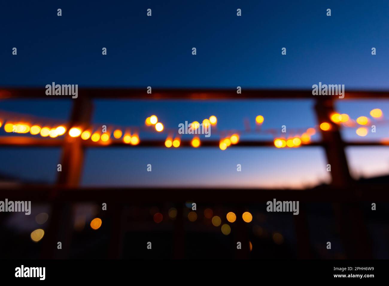 Out of focus christmas lights on the railings of a balcony at night ...