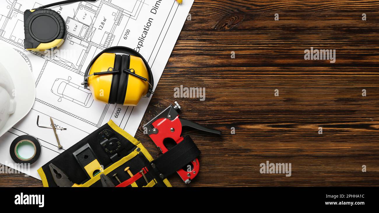 Hearing protectors with builder's tools and house plan on wooden ...