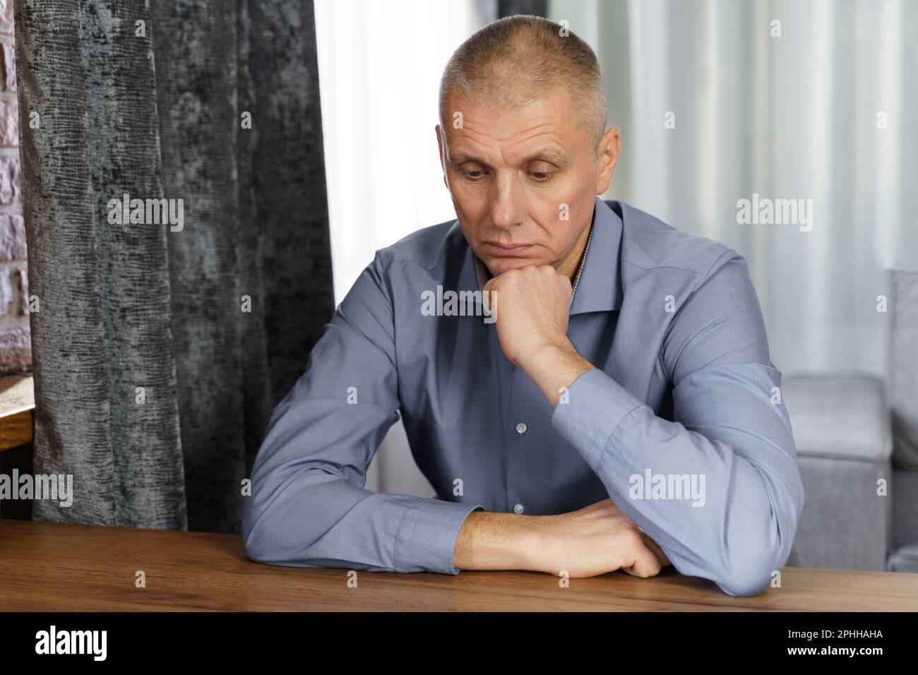 Portrait of a pensive middle-aged man sitting at a table. The man ...