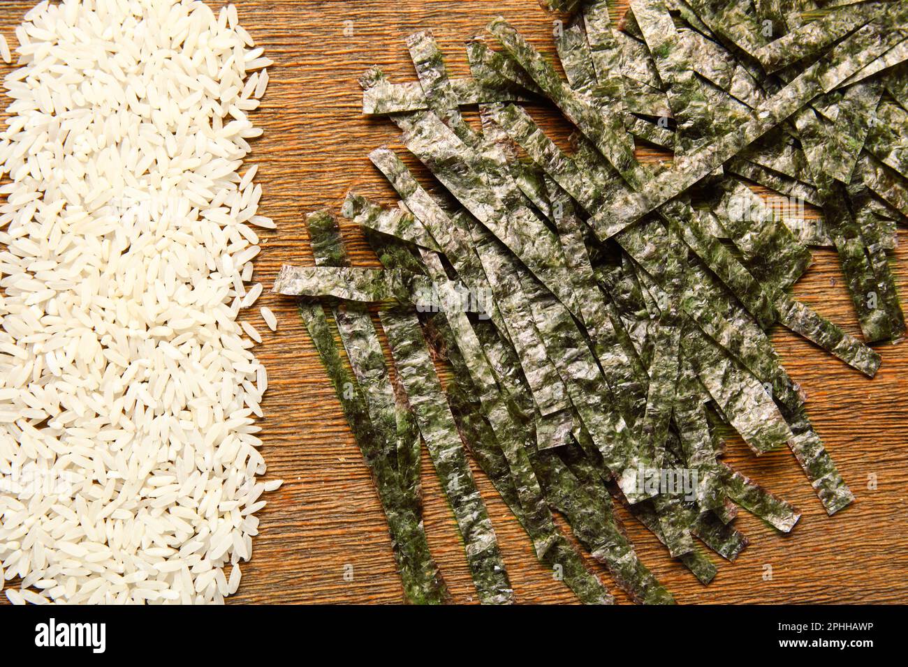 Wooden board with rice and cut nori sheets, closeup Stock Photo - Alamy