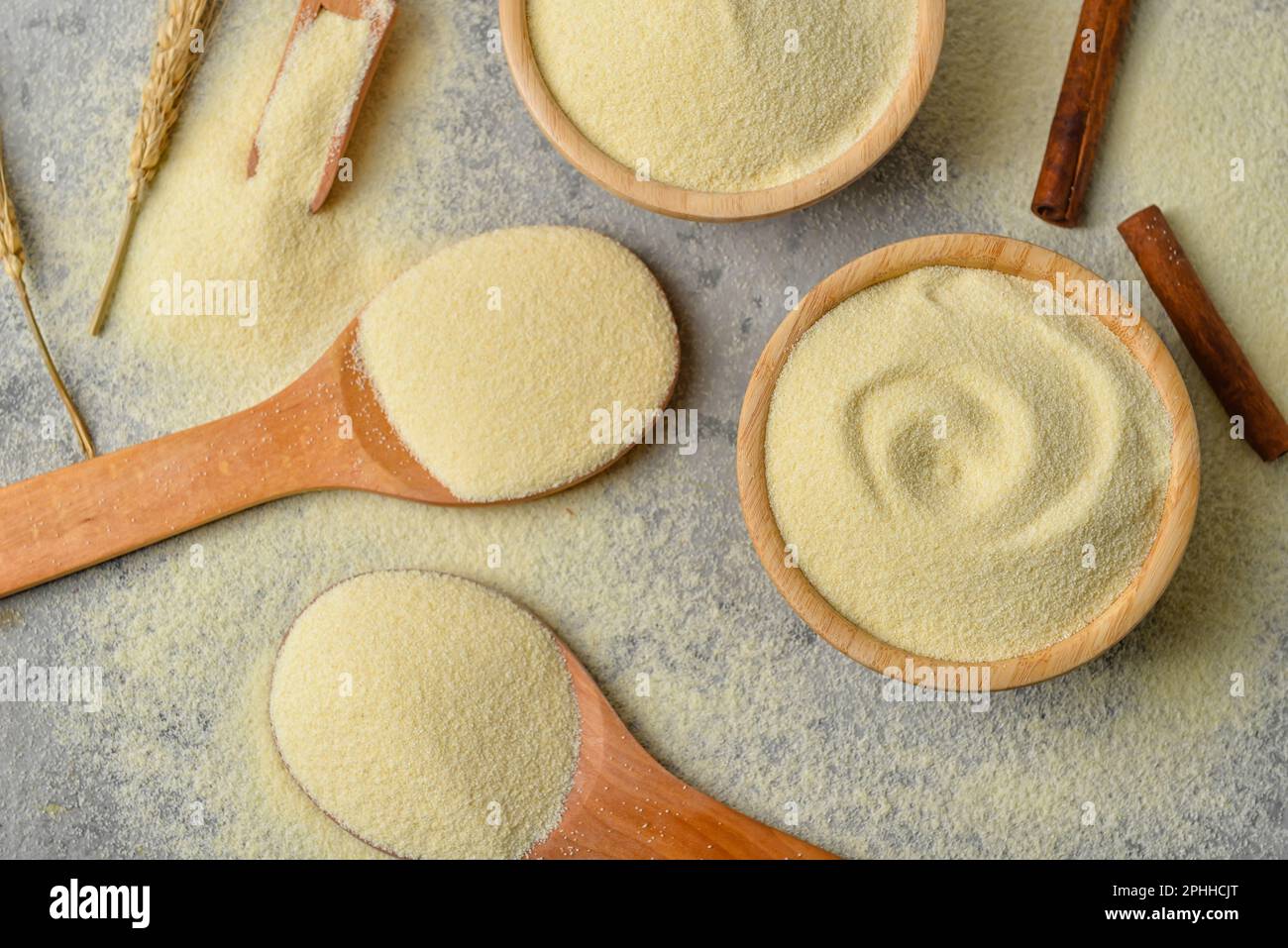 Bowls of raw semolina, cinnamon and spikelets on grunge background ...