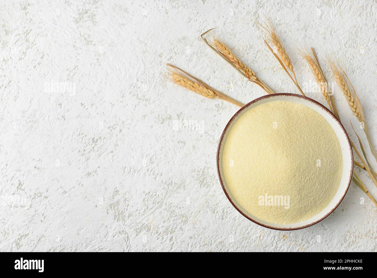 Bowl of raw semolina and spikelets on white background Stock Photo - Alamy