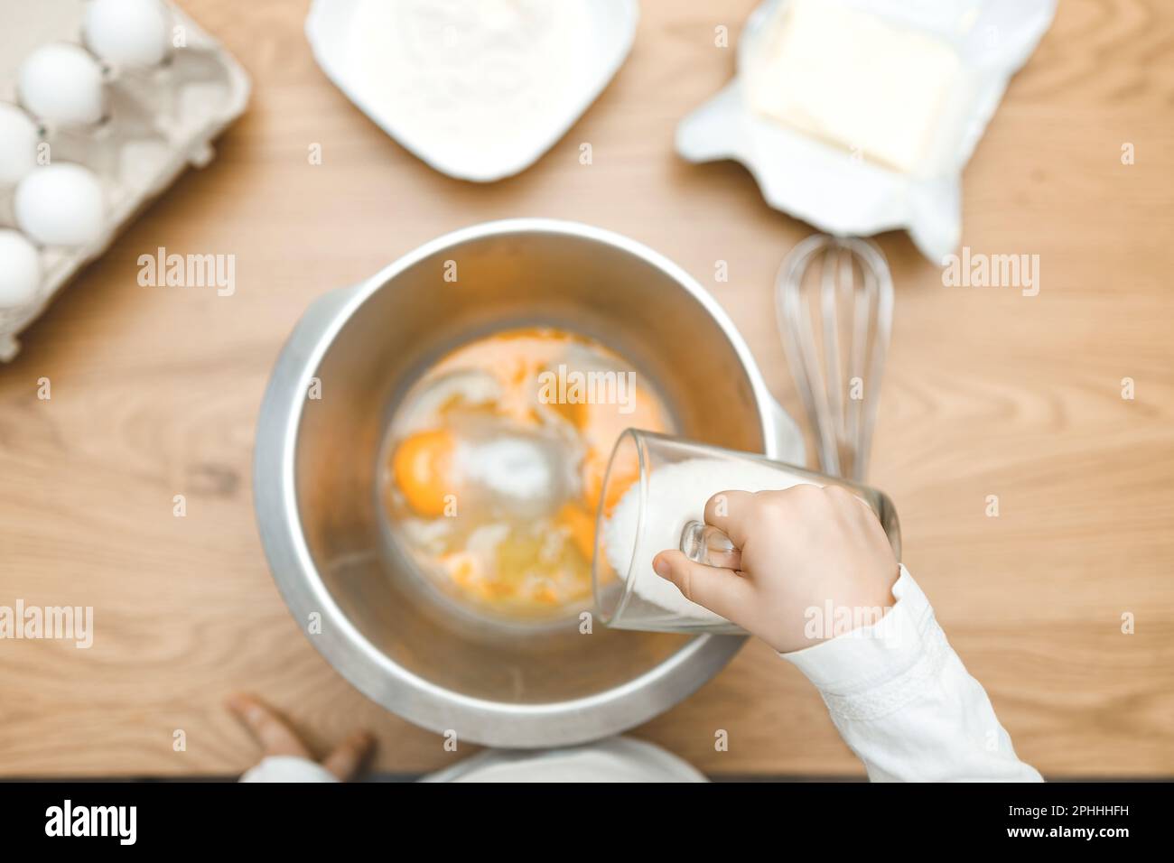 Kid's hands sprinkling sugar. Eggs, butter, flour. Cooking ingredients ...