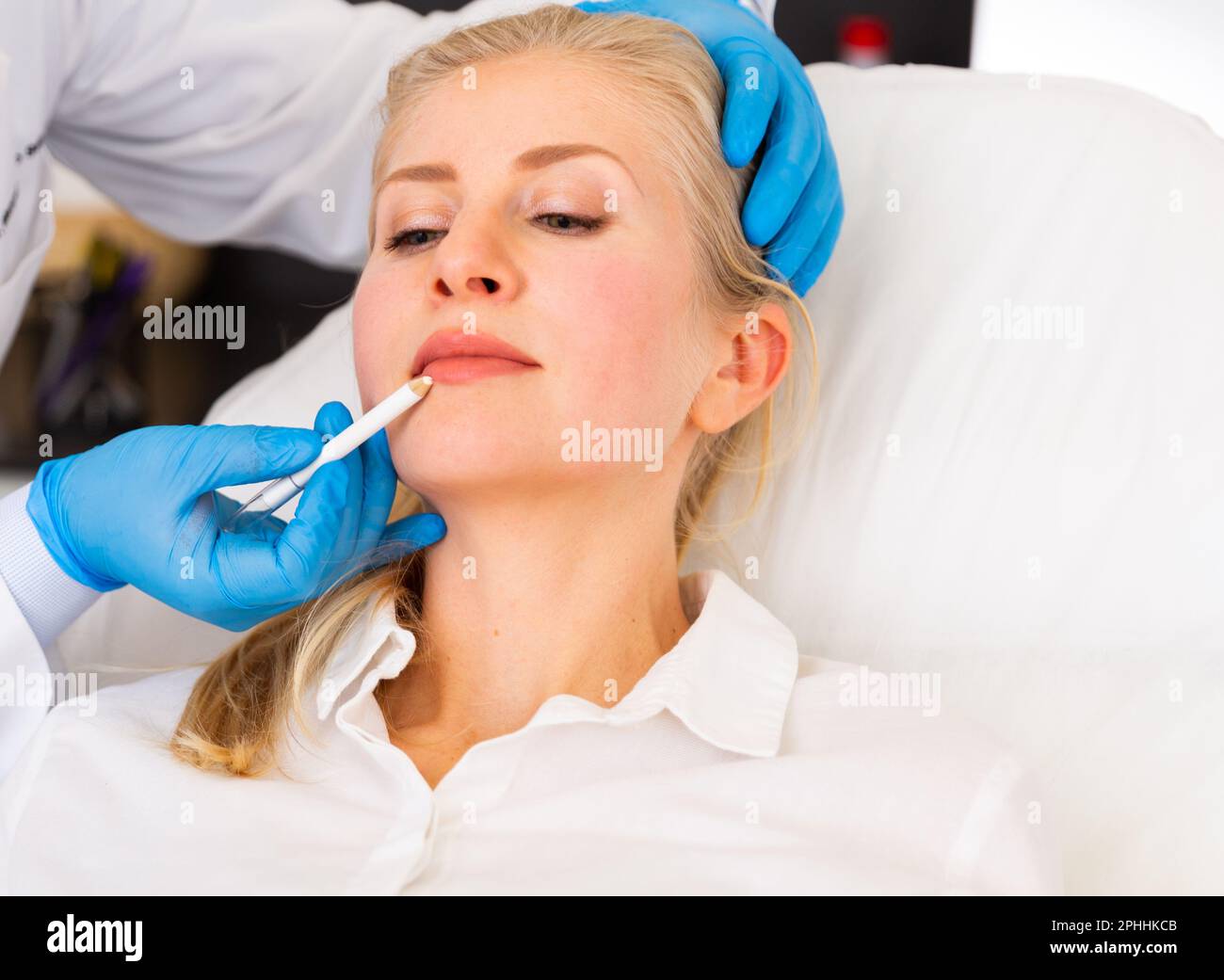 Cosmetologist applying marks on face of young female client Stock Photo ...