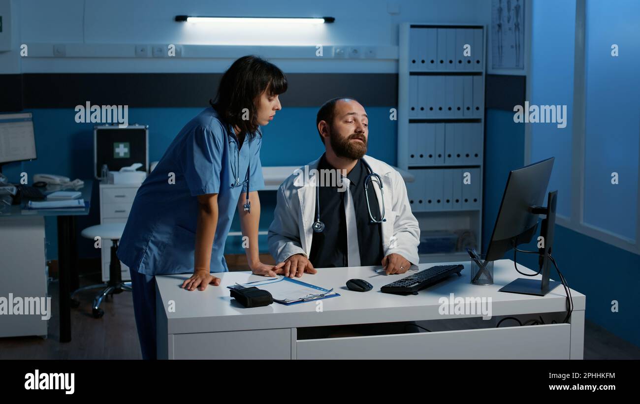 General practitioner and assistant working over hours in office ...