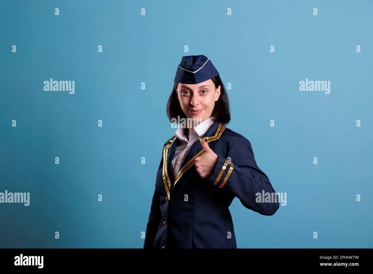 Portrait of smiling flight attendant making thumbs up gesture while ...