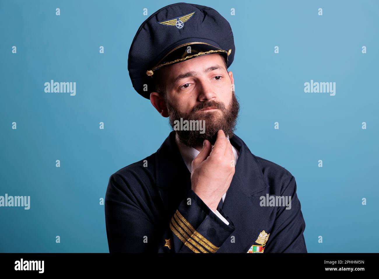 Thoughtful unsure airline pilot in uniform thinking, touching chin ...