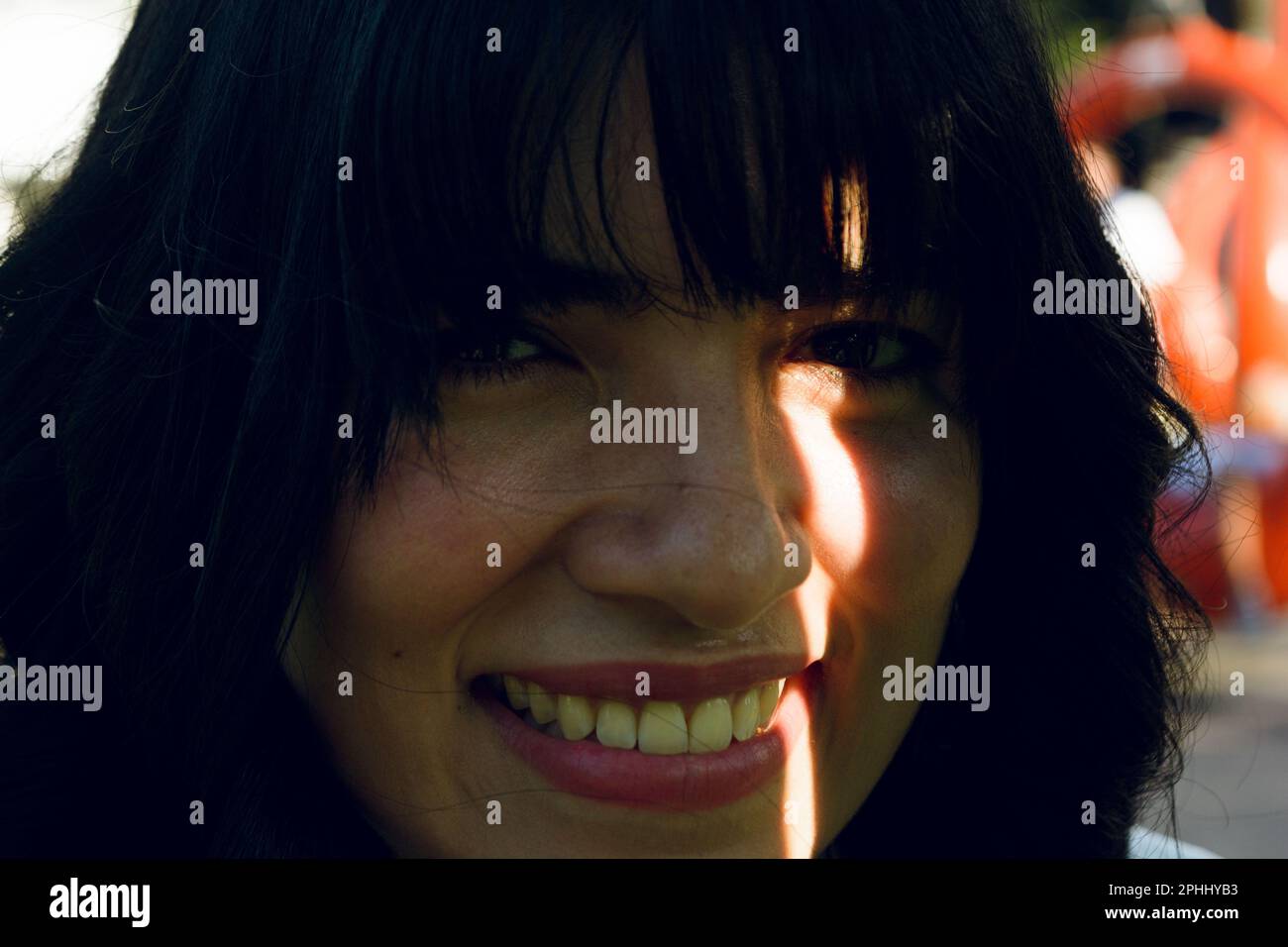 close-up portrait of young latin woman, smiling in shadow with a line ...