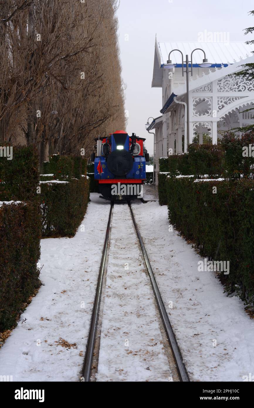 Colorful train seen behind railway under snow. Train parked and ...