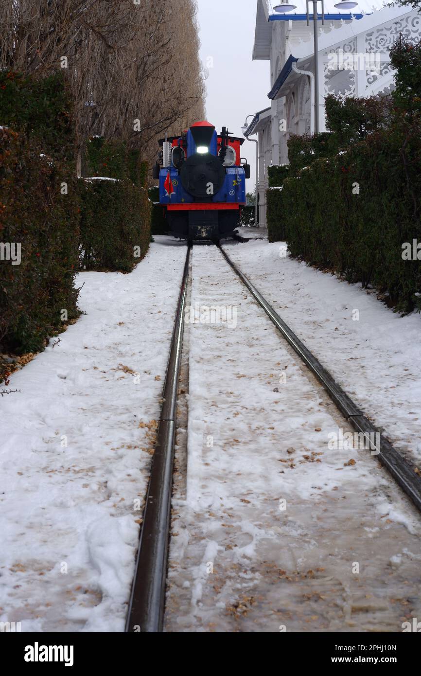 Colorful train seen behind railway under snow. Train parked and ...