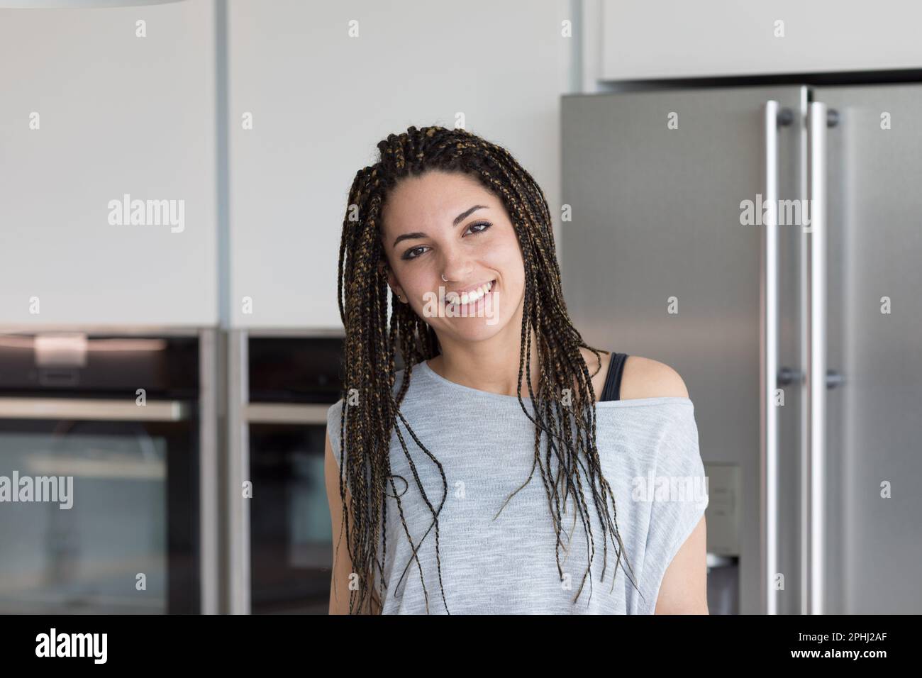 Beautiful happy young woman in a modern kitchen with gray tones. She ...