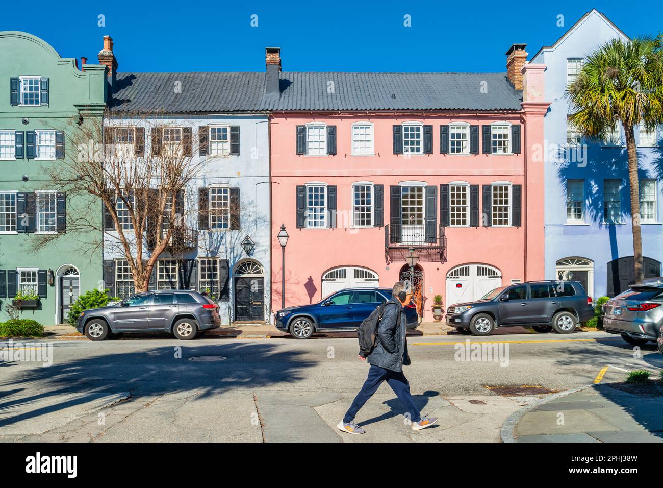 Pedestrians crosses street in front of Rainbow Row, a set of historic ...