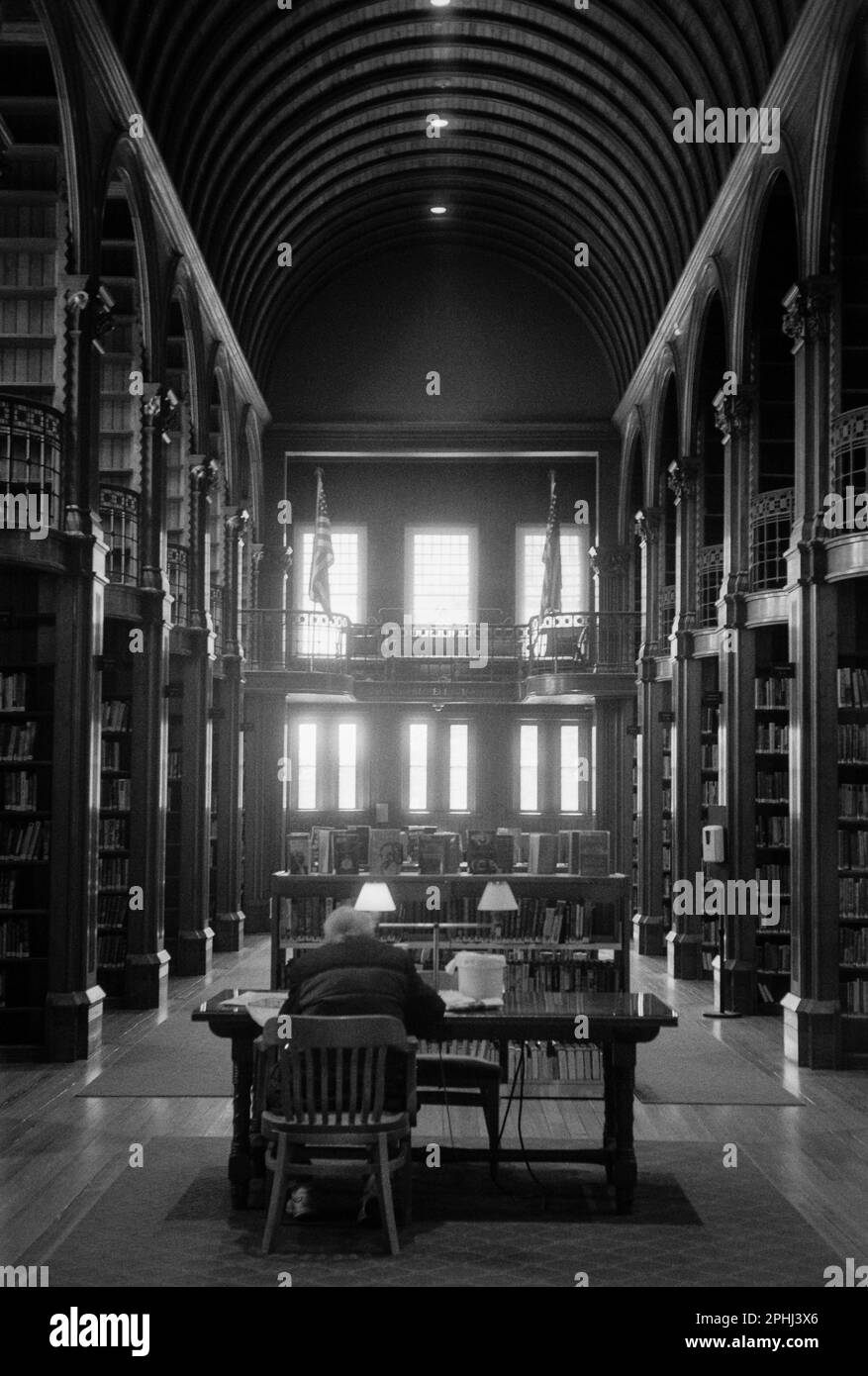 A man sits reading a newspaper at a table in the study hall of the ...