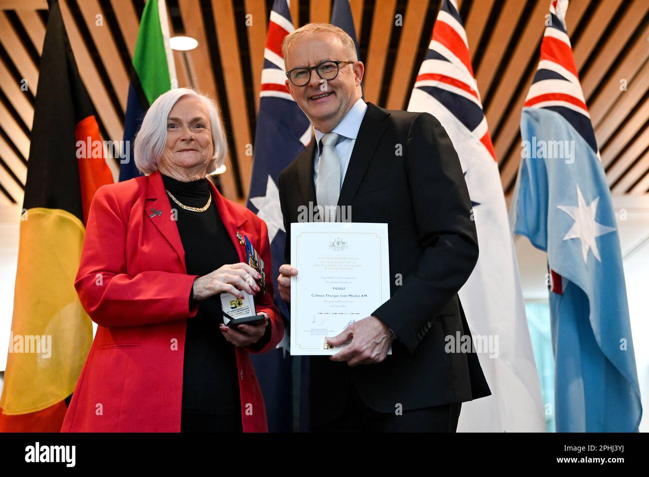 Australian Prime Minister Anthony Albanese (right) hands over a ...