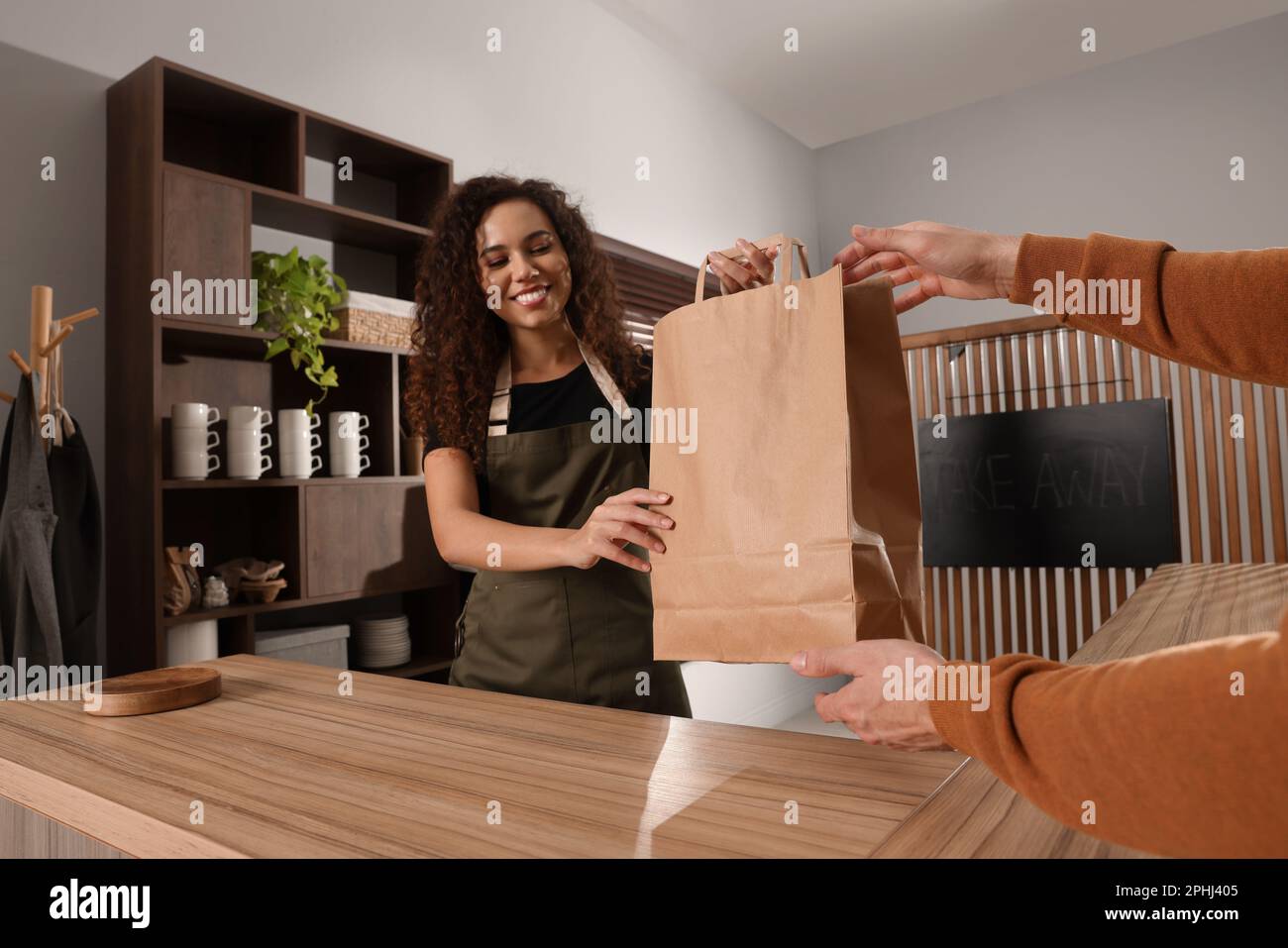 Worker giving paper bag to customer in cafe Stock Photo - Alamy