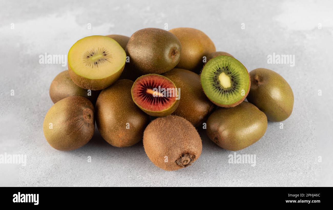 Different Varieties Of Kiwi Lie In A Pile On The Table Halves Of Red