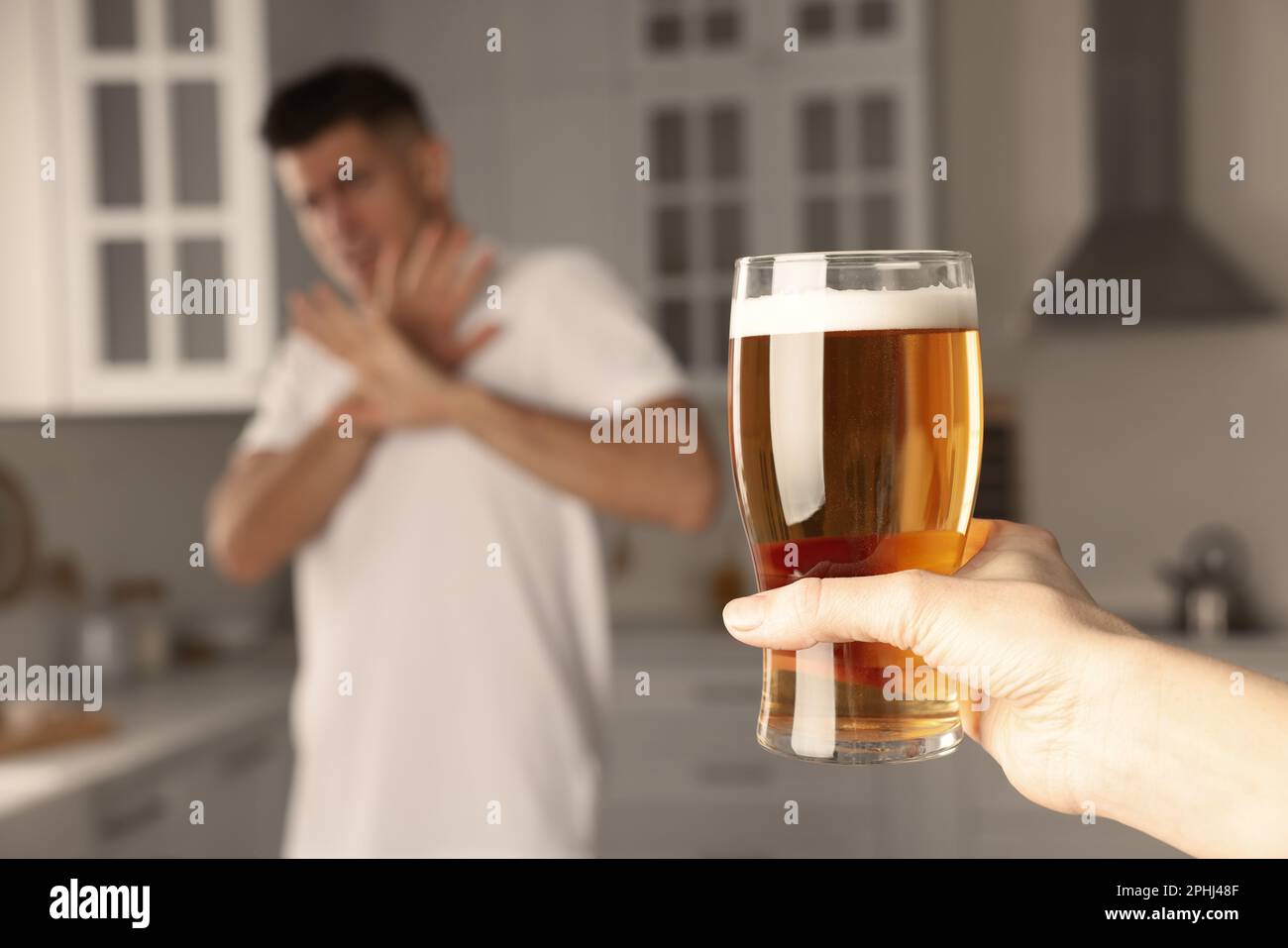 Man refusing to drink beer in kitchen, closeup. Alcohol addiction ...