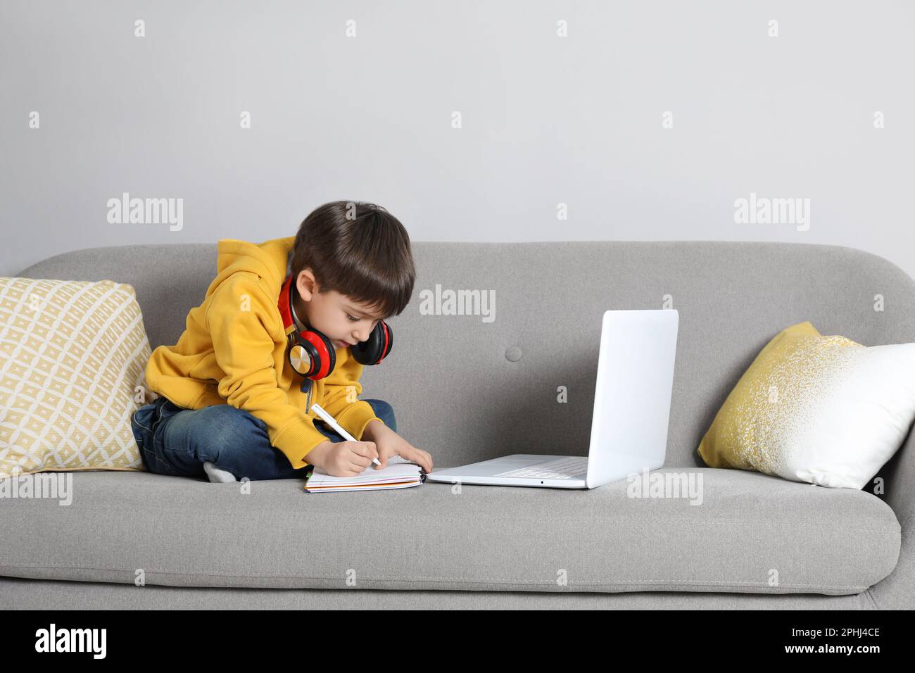 Cute little boy with modern laptop studying online at home. E-learning ...