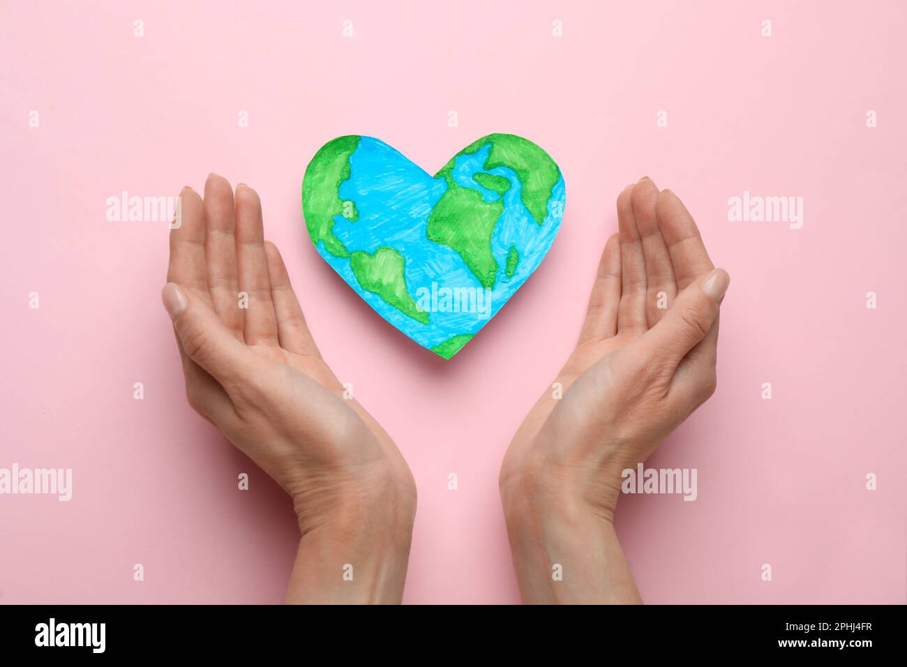Woman and heart shaped model of planet on pink background, flat lay ...