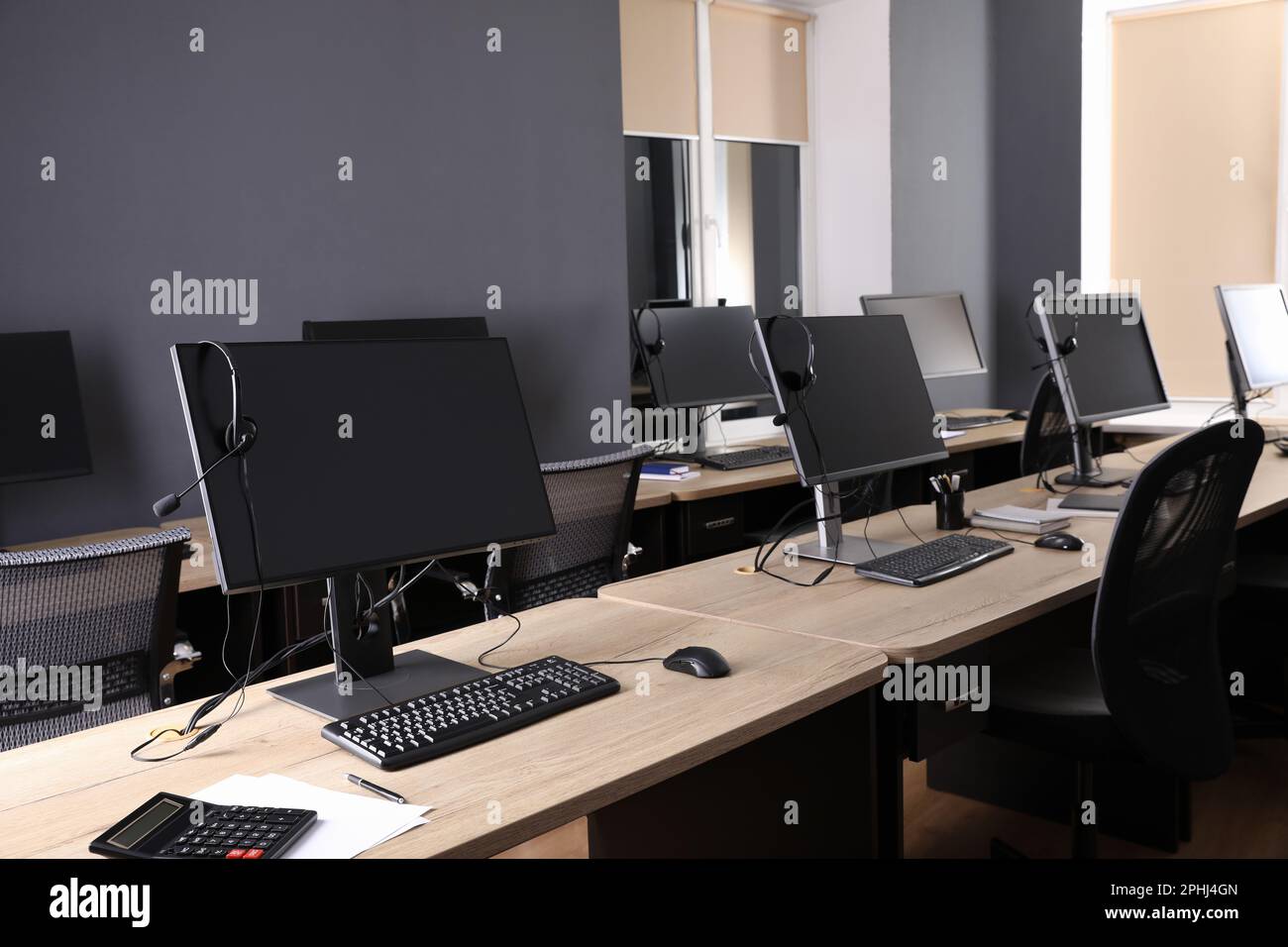 Modern computers with headsets on wooden desk in office. Hotline ...