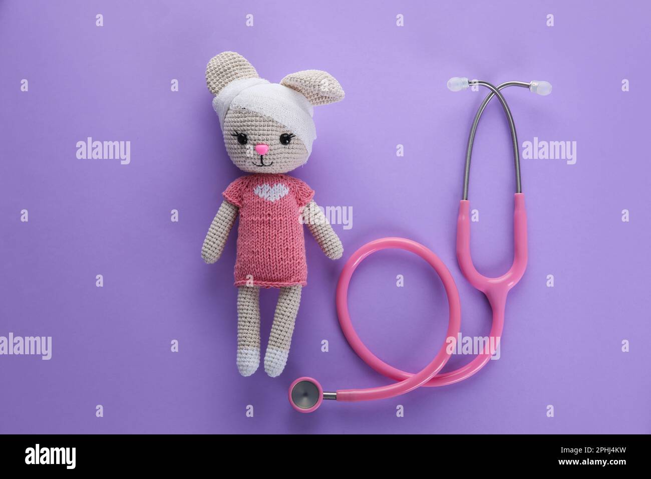 Cute toy bunny with bandage and stethoscope on violet background, flat ...