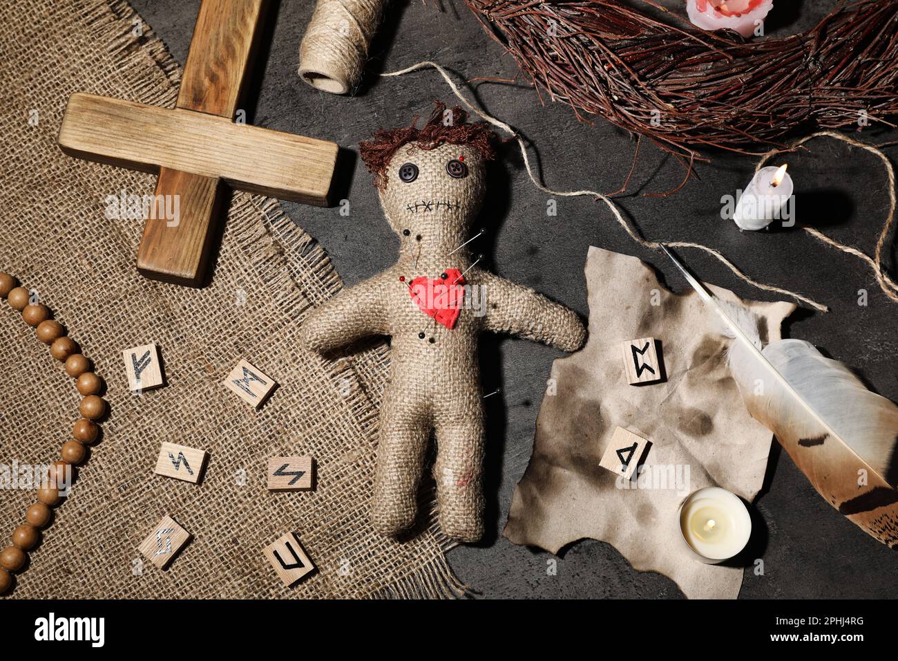 Voodoo doll pierced with pins and ceremonial items on grey table, flat ...