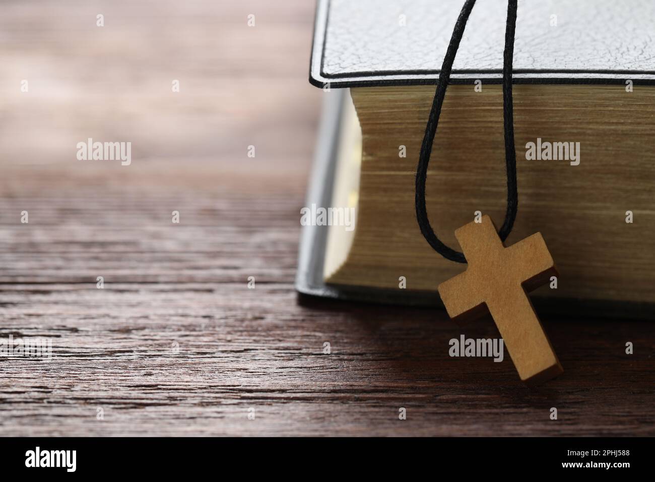 Wooden Christian cross and Bible on table, closeup. Space for text ...