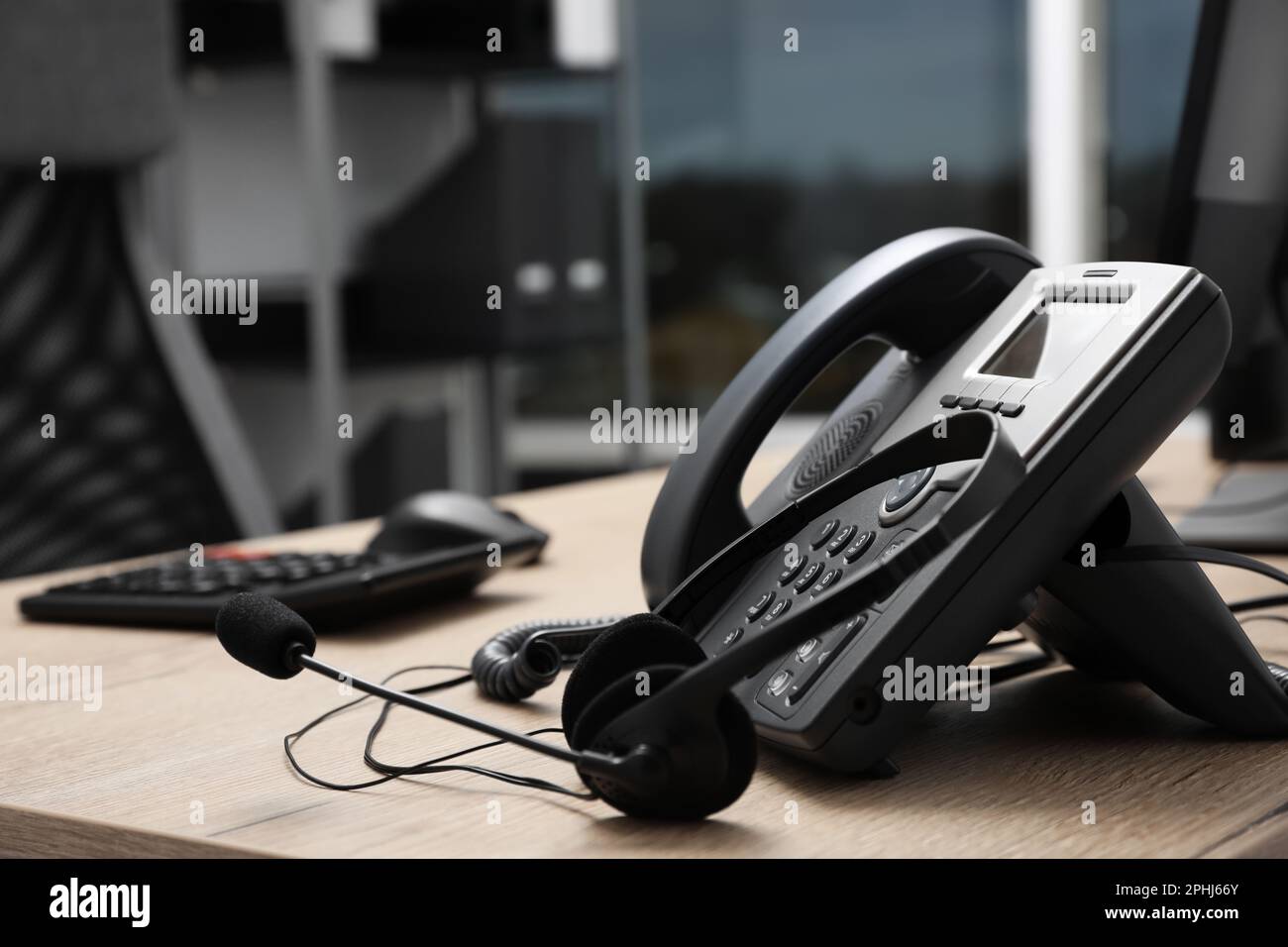 Stationary phone and headset on wooden desk indoors. Hotline service ...