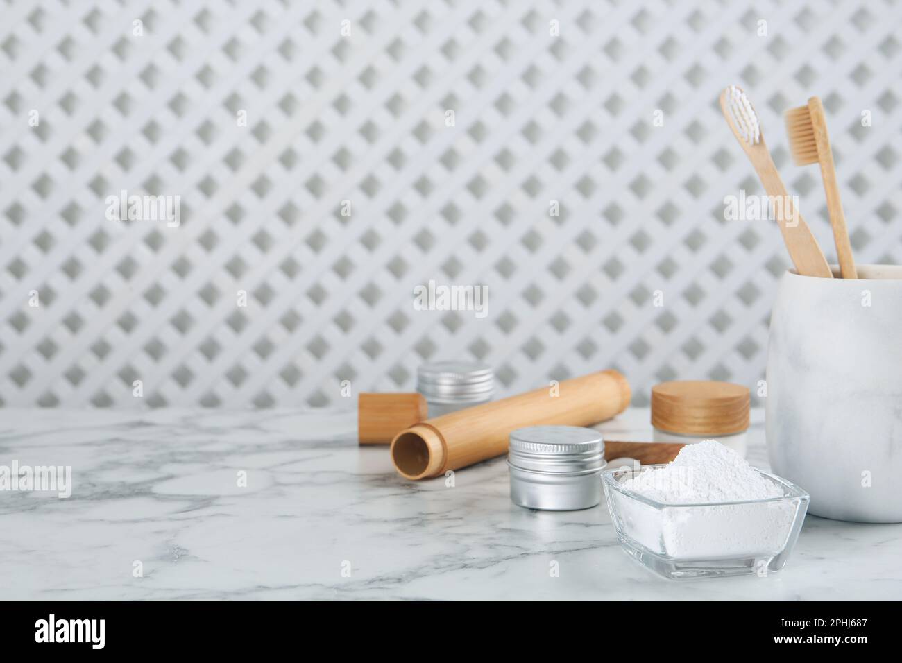 Tooth powder, brushes and jars on white marble table, space for text ...