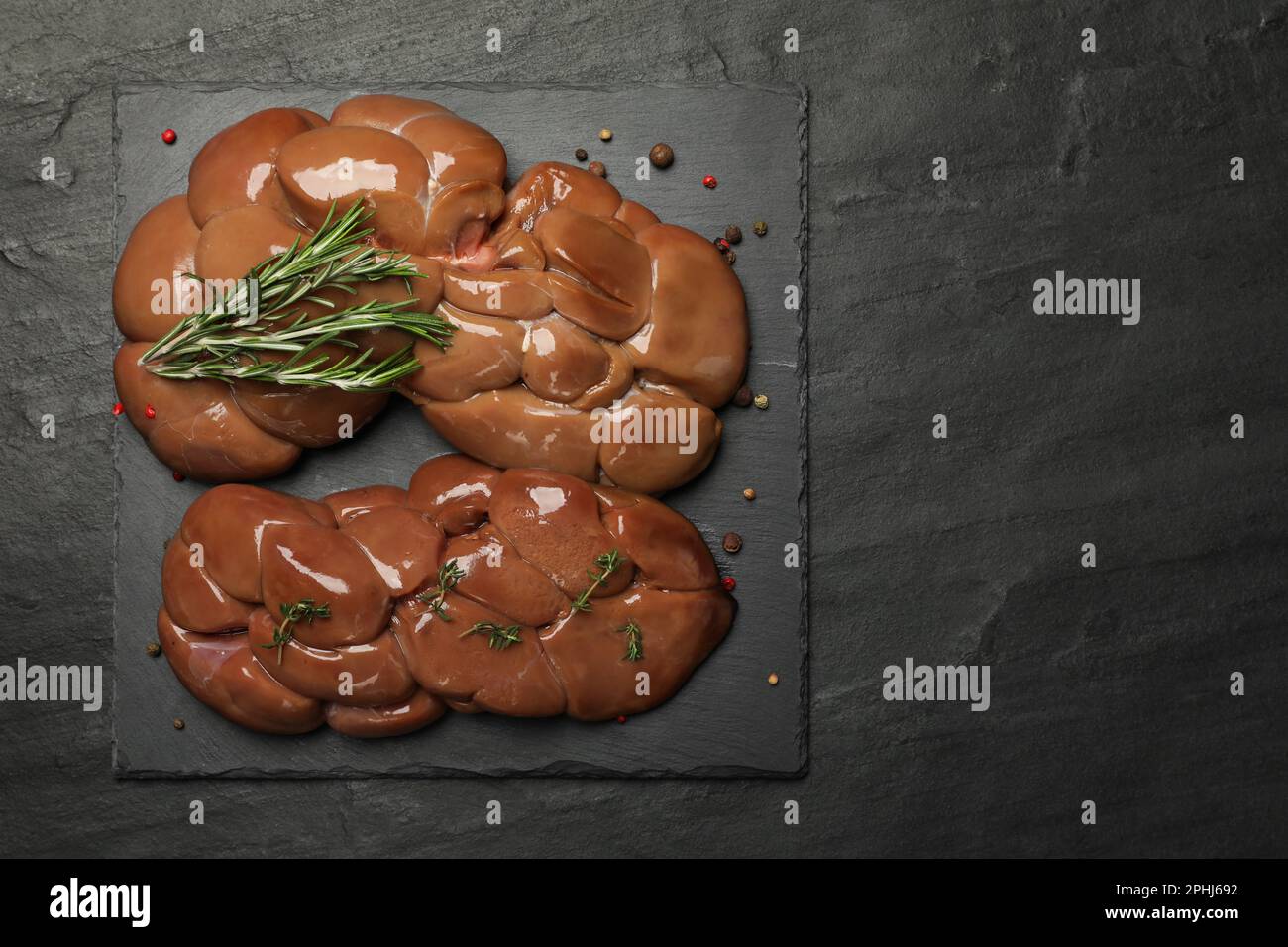 Fresh raw kidneys with rosemary and thyme on black table, top view ...