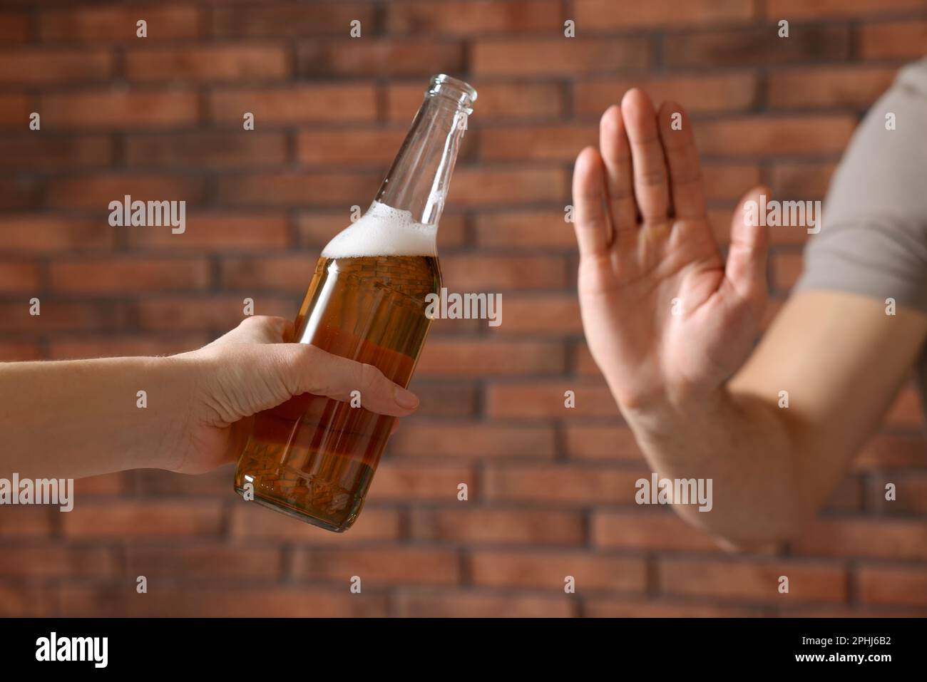 Man refusing to drink beer near red brick wall, closeup. Alcohol ...