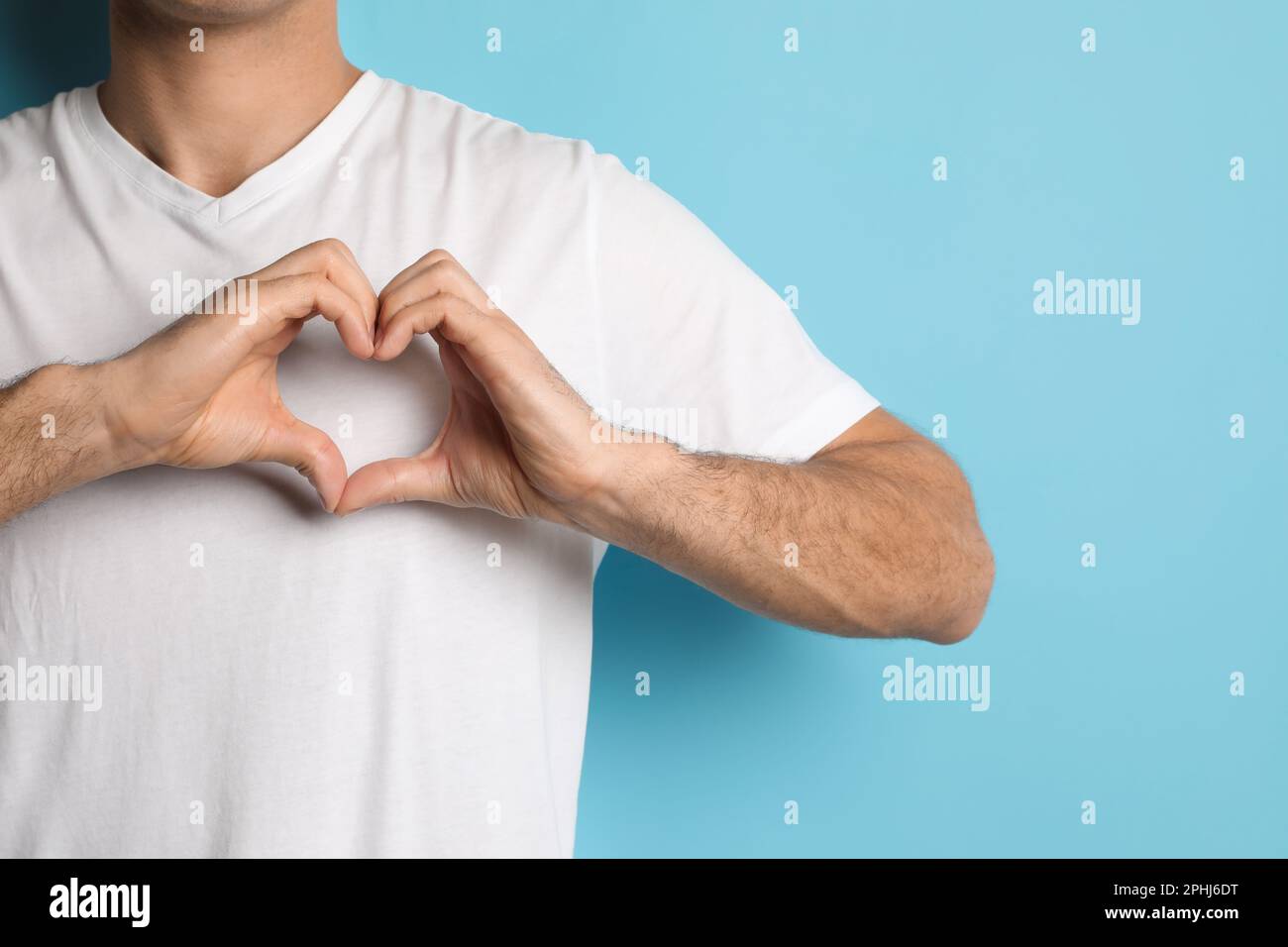 Man making heart with hands on light blue background, closeup. Space ...