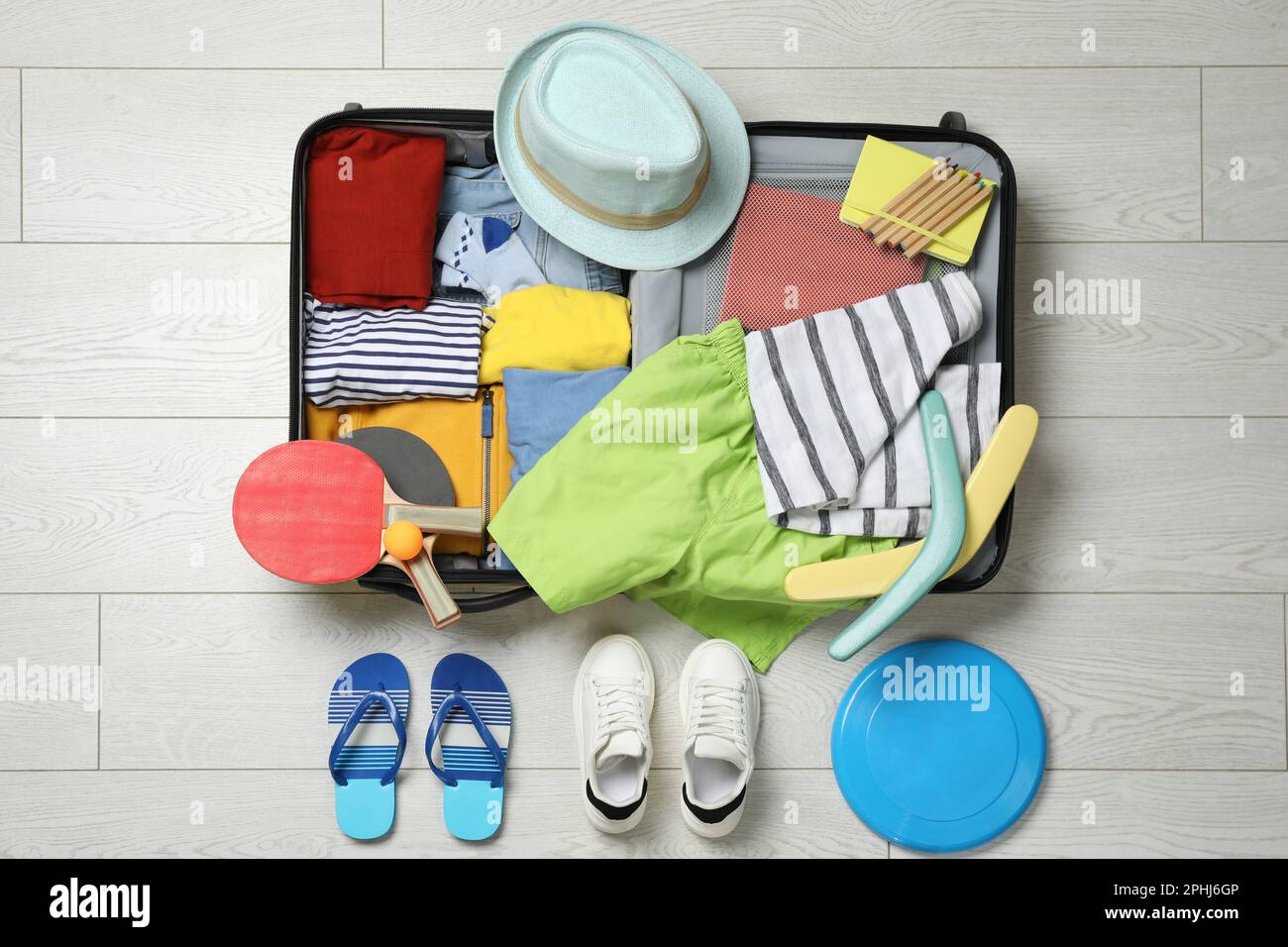 Open suitcase with stylish clothes, accessories, sport equipment and ...