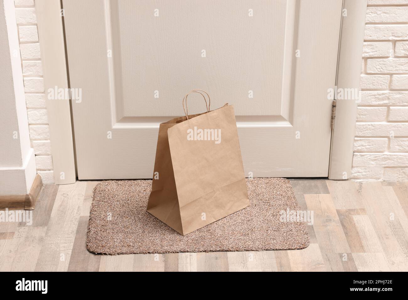 Paper bag on door mat near entrance indoors Stock Photo - Alamy