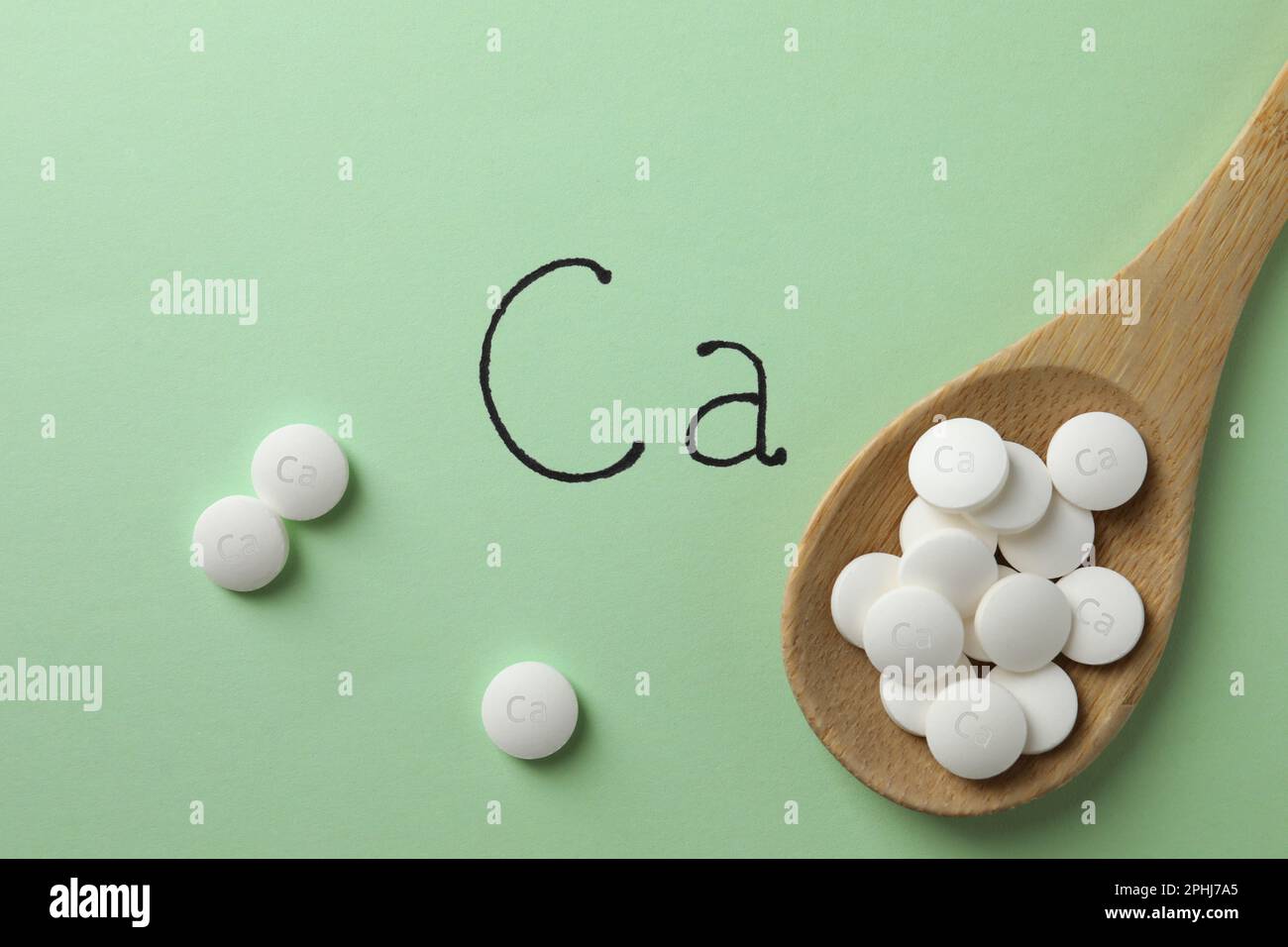 Flat lay composition with calcium supplement pills on light green ...