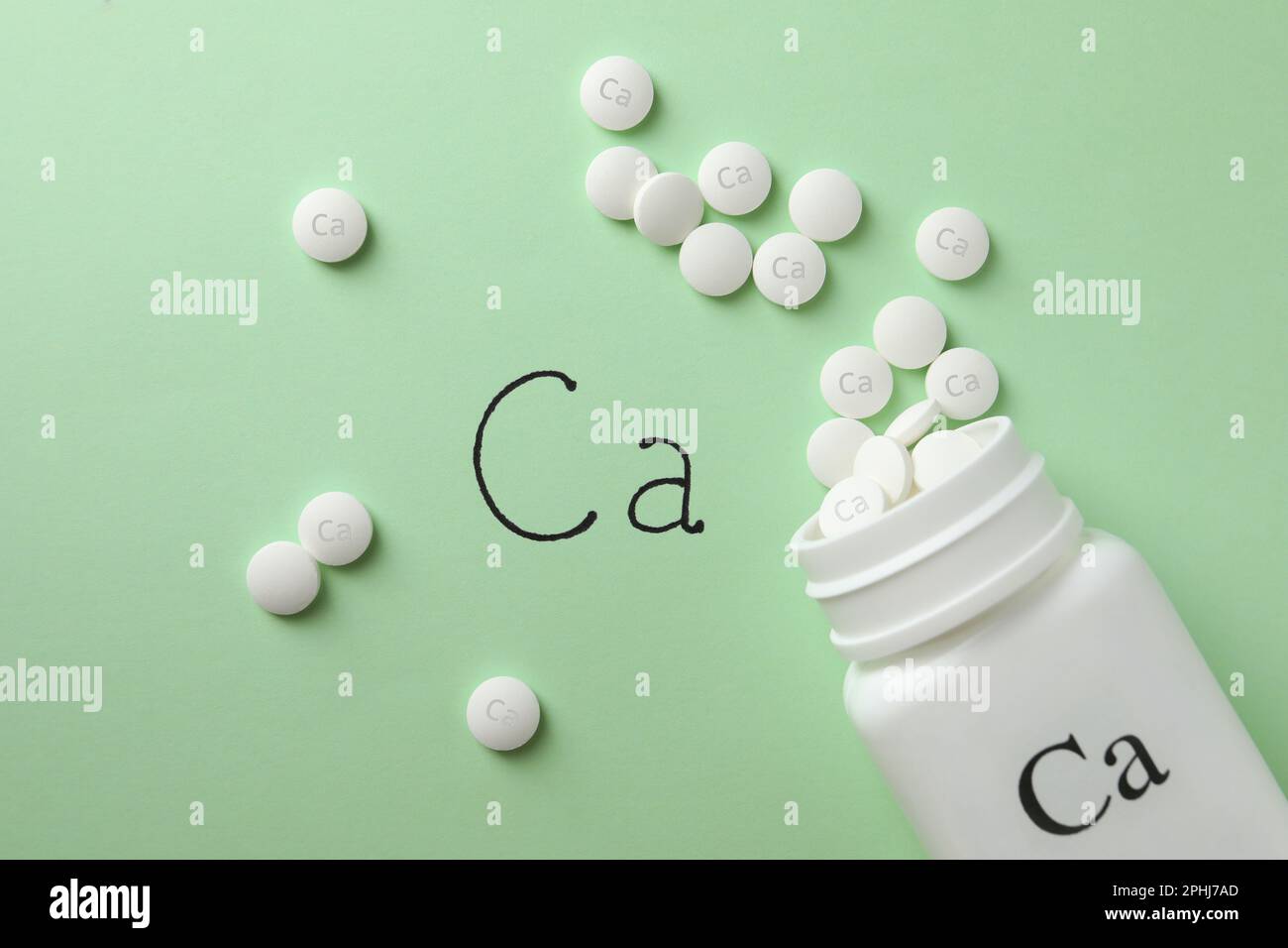 Flat lay composition with calcium supplement pills on light green ...