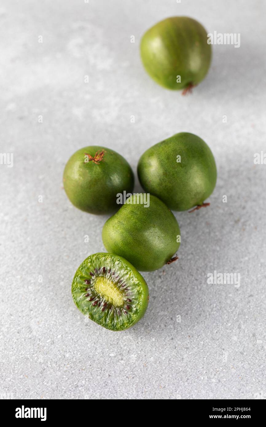 Mini kiwi on a gray table, whole and half. Tropical fruits. Kiwi berry ...
