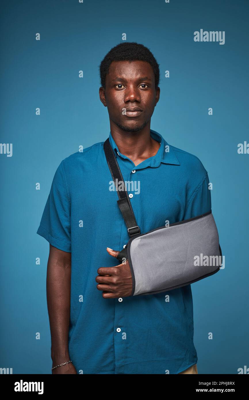 Vertical portrait of young black man wearing arm sling against vibrant ...