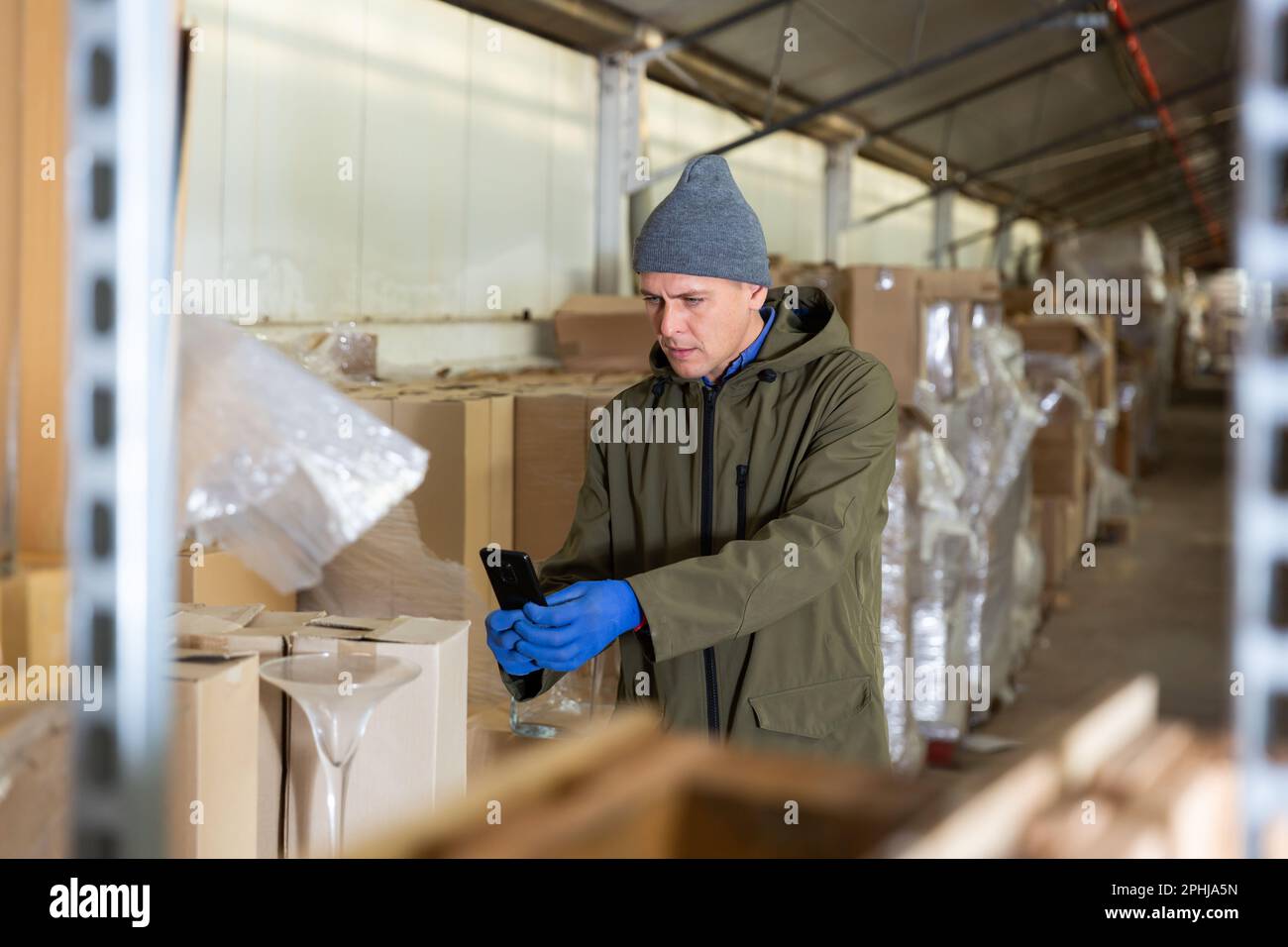 Store worker scans qr code on boxes using smartphone in warehouse shop ...