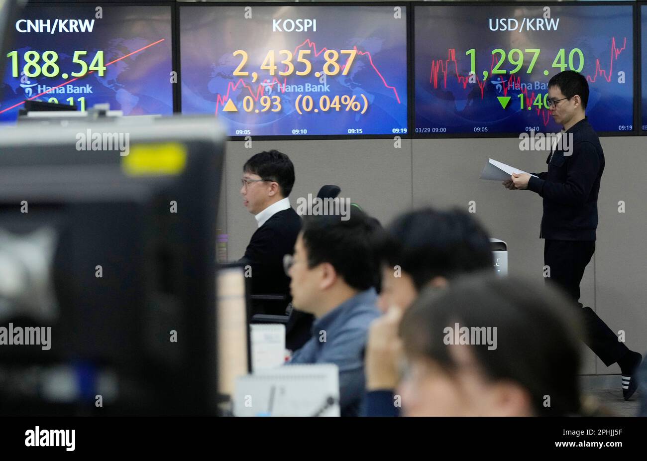 A currency trader passes by the screens showing the Korea Composite ...
